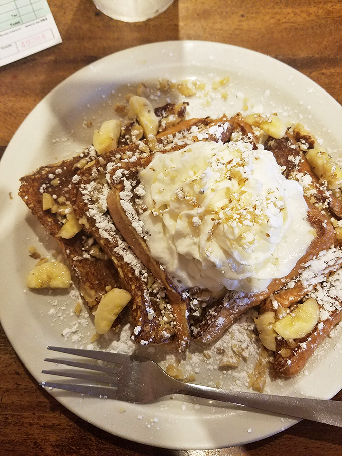 French toast that's dressed for success with powdered sugar, whipped cream, and bananas – breakfast masquerading as dessert, and nobody's complaining.