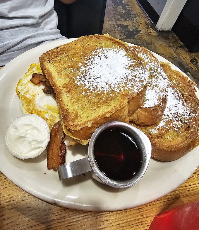 French toast that's achieved the impossible balance – crisp exterior giving way to custardy interior, with powdered sugar falling like delicious snow.