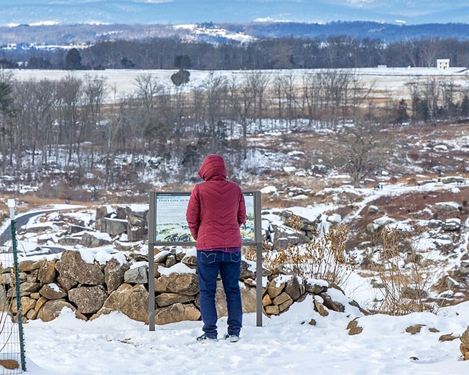 A visitor contemplates the battlefield's quiet power, where interpretive signs help modern travelers understand the momentous events that unfolded on this hallowed ground.
