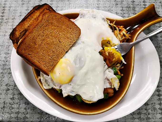 Breakfast architecture at its finest—eggs perched atop a foundation of toast with crispy hash browns playing a supporting role.