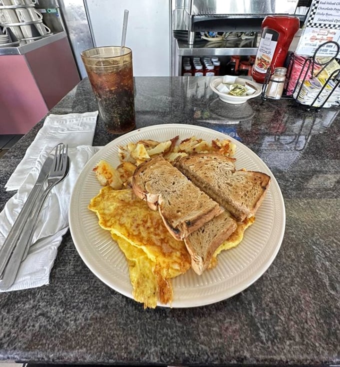 Breakfast perfection on a plate—golden omelet, crispy home fries, and toast standing by for important yolk-sopping duties. This is why morning people exist.