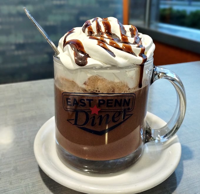 Hot chocolate elevated to an art form – topped with a cloud of whipped cream and chocolate drizzle in a mug that means business.