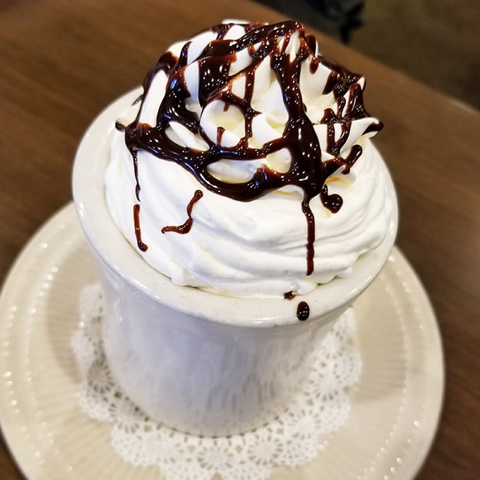 This isn't just hot chocolate—it's a mountain of whipped cream with chocolate drizzle that happens to have hot chocolate underneath. Dessert disguised as a beverage!