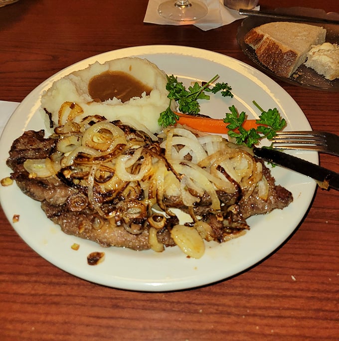 Liver and onions—the dish that separates casual diners from true comfort food aficionados—caramelized to sweet-savory perfection atop a bed of buttery mashed potatoes.