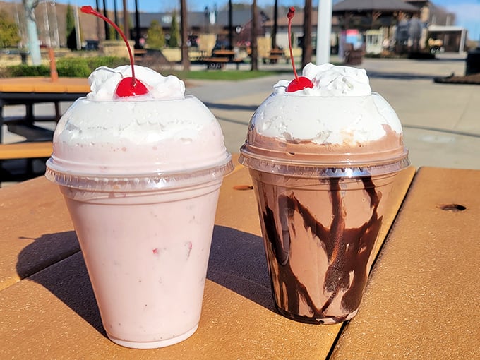 Milkshakes crowned with whipped cream and cherries – one strawberry, one chocolate – standing tall like the dessert version of American Gothic.