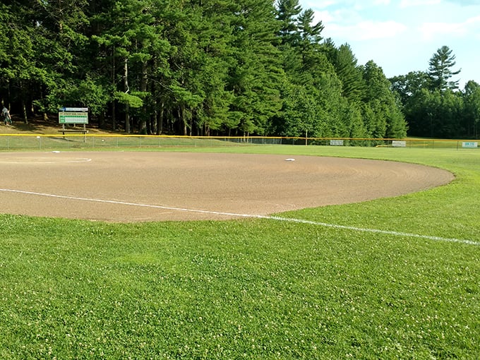 This baseball diamond waits patiently for summer games where parents cheer wildly for kids who are mostly just hoping for post-game ice cream.