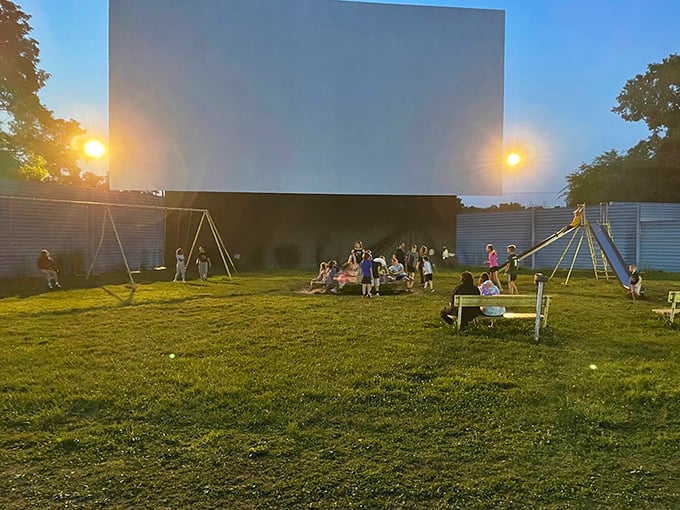 Twilight at the drive-in: where children play tag with their shadows while parents set up the perfect viewing nest.
