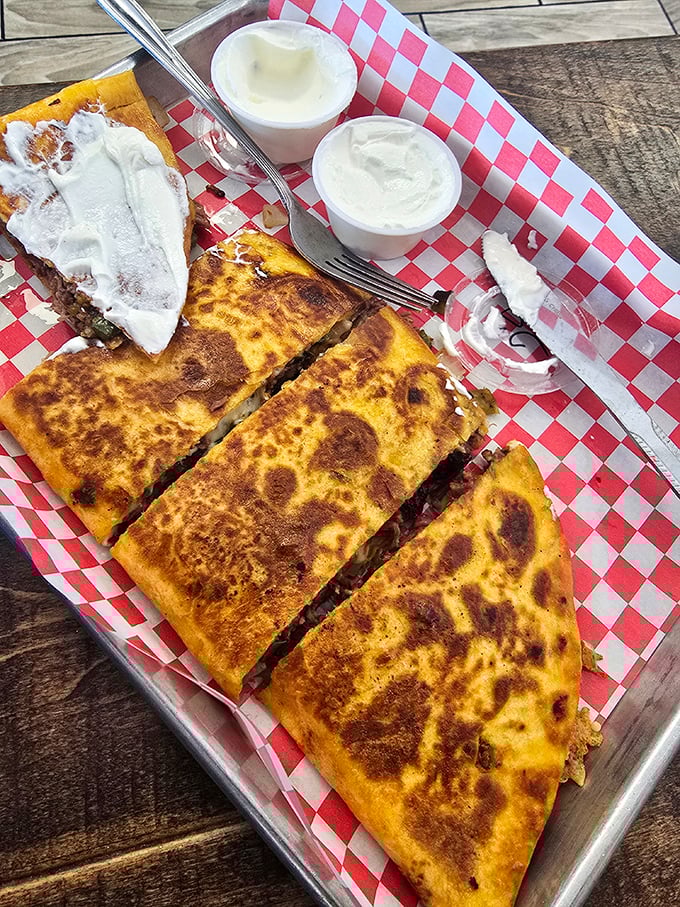 Golden-brown quesadilla perfection served with a dollop of sour cream. Proof that simple food done right transcends all culinary boundaries.