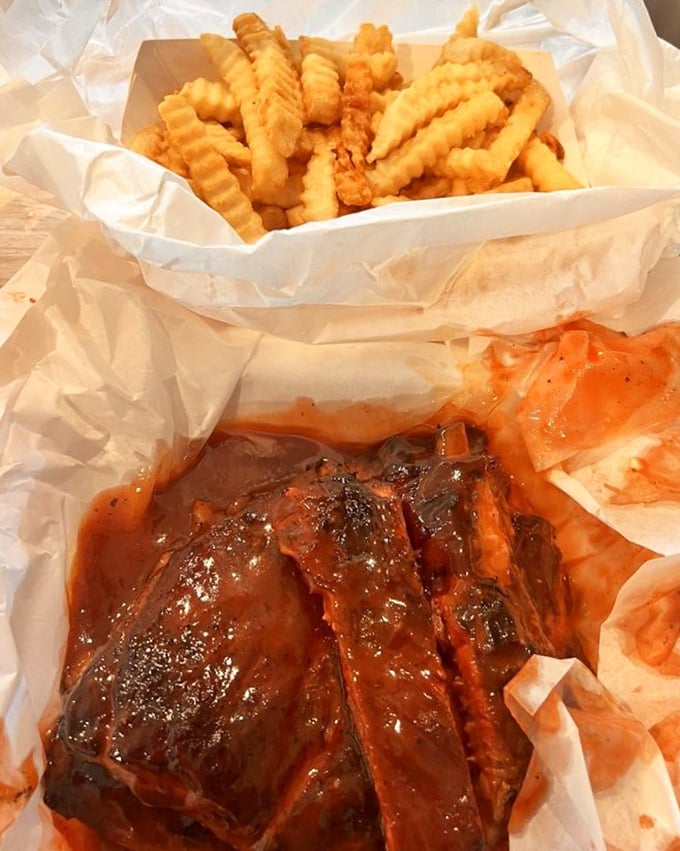 Ribs and fries nestled in paper—the lunch combo that's launched a thousand napkins. Worth every sauce-stained shirt in history.