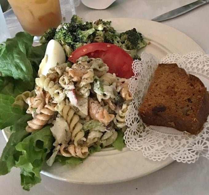 A pasta salad that doesn't apologize for being exactly what it is – fresh, vibrant, and substantial. That doily under the bread is a charming touch of old-school class.