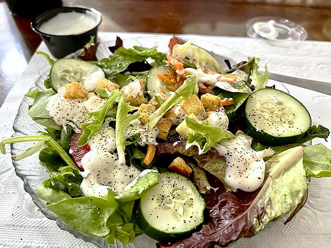A salad this fresh deserves respect—crisp greens, cucumber slices, and house-made dressing prove vegetables aren't just an afterthought at Old Salty's.
