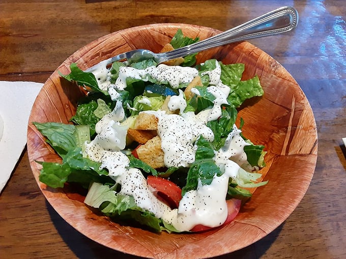 Even the salad gets the wooden bowl treatment – crisp greens, fresh veggies, and dressing that wasn't poured from a bottle that's been sitting around since 2019.