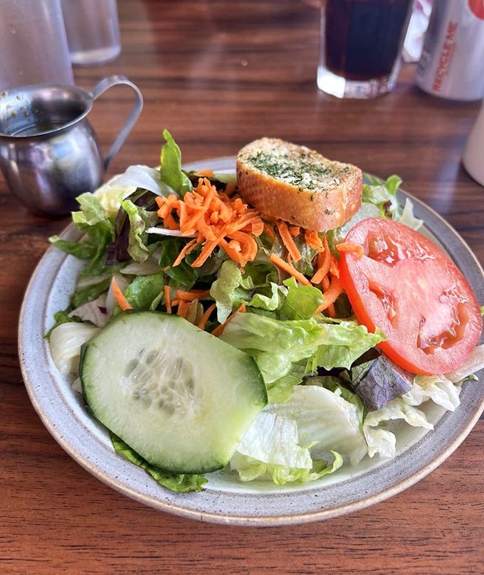 A side salad that actually tries—crisp greens, vibrant veggies, and that slice of tomato looking like it just came from someone's garden.