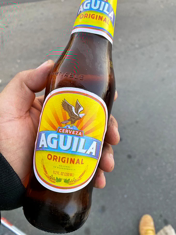 An ice-cold Aguila beer stands ready for duty—the perfect companion when facing down a burrito that could feed a small village.