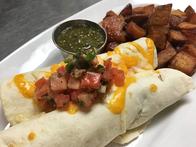 Breakfast burrito perfection—cheese melting like sunrise, fresh salsa adding zing, and those home fries looking like they've been kissed by the gods of crispiness.