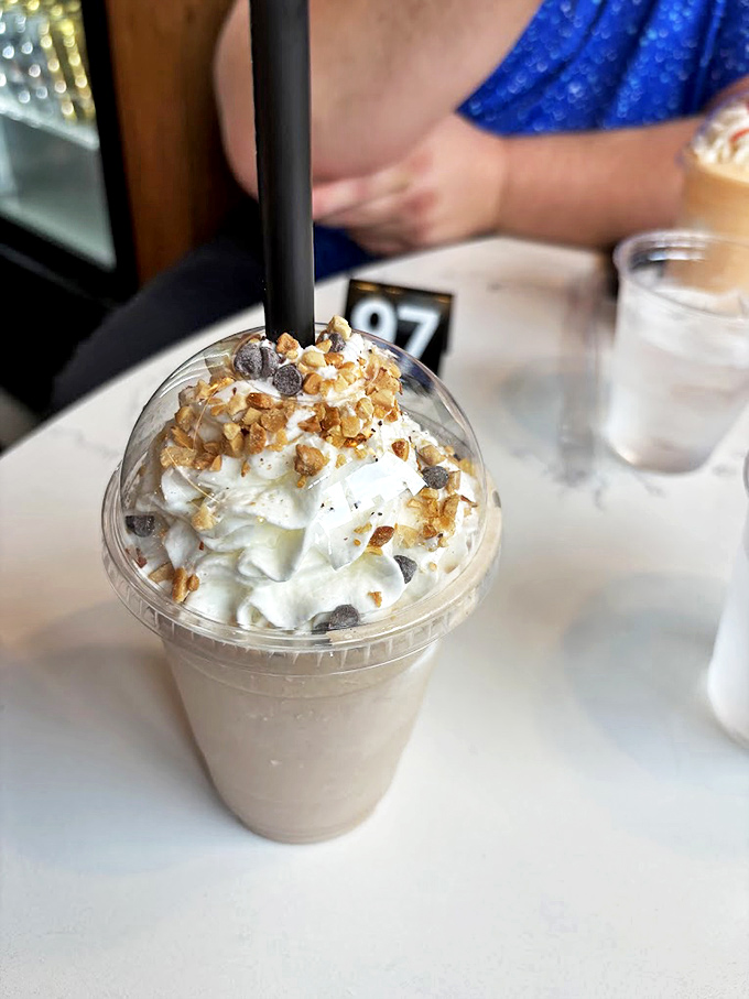 This isn't just a milkshake; it's a Butterfinger masterpiece topped with whipped cream and crunchy bits—dessert masquerading as a beverage.