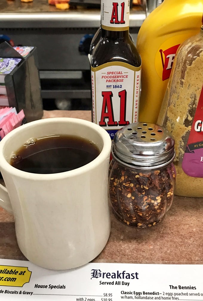 That thick white mug holds the lifeblood of morning warriors—honest diner coffee that doesn't need fancy Italian names to get the job done.