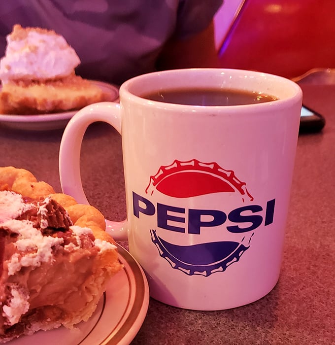 Coffee in a Pepsi mug with pie on standby—the diner equivalent of having your accountant on speed dial during tax season. Essential.