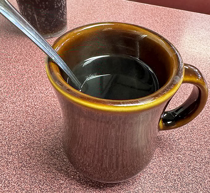 That brown ceramic mug isn't just holding coffee—it's cradling liquid motivation in the unpretentious vessel every proper diner deserves.