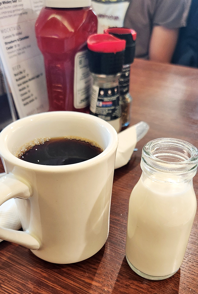 The classic diner coffee ritual—dark brew in a sturdy mug with milk in those adorable little bottles. Morning meditation, Jersey-style.