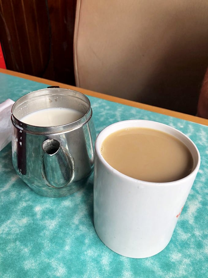 The coffee comes in classic diner white mugs with metal creamers standing by—no fancy latte art needed when the brew is this good.