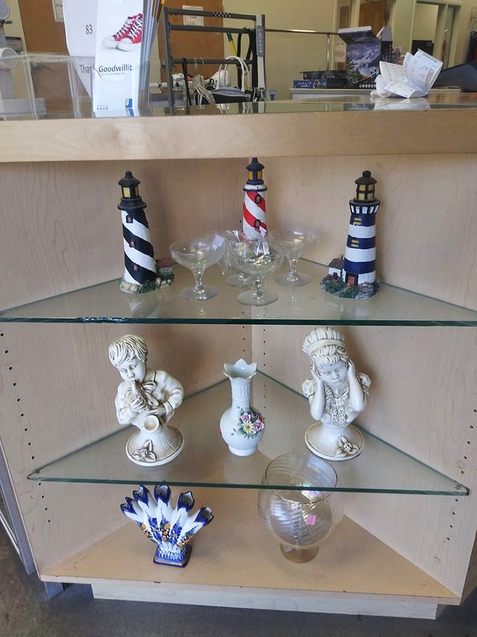 Lighthouse sentinels and porcelain figurines stand at attention on glass shelves—coastal charm meets southwestern thrift store magic.