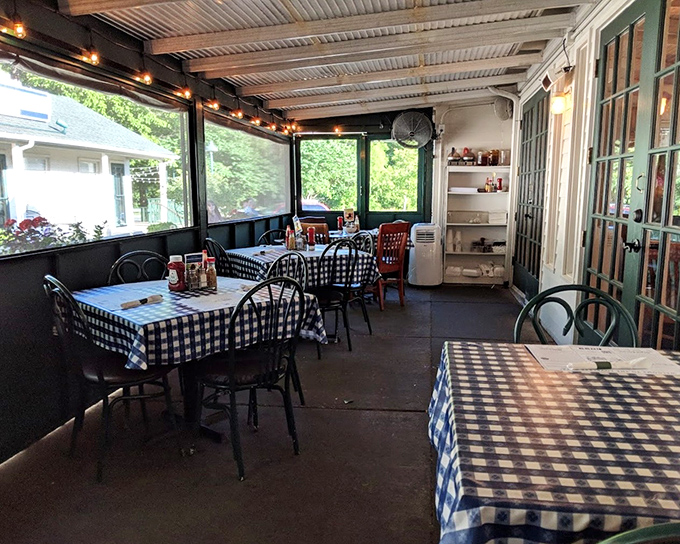 The screened porch dining area offers a breezy Southern experience. Those blue checkered tablecloths aren't just decoration – they're a promise of good things to come.