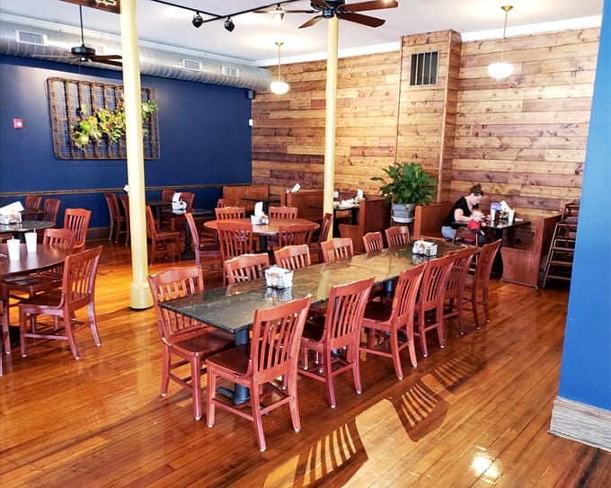 The dining room balances rustic charm with urban cool—wooden walls, blue accents, and tables large enough for family-style feasting or making new friends.