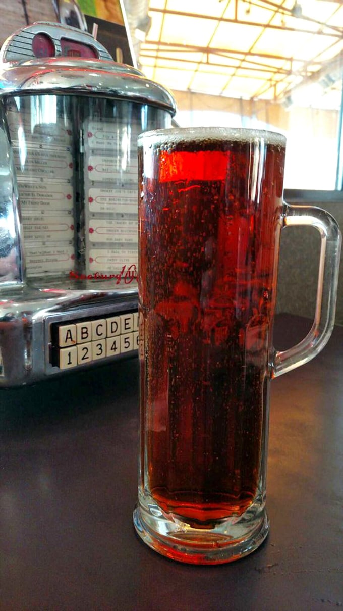 That tall, frosty glass of soda beside a vintage jukebox selector – pure Americana in liquid form.