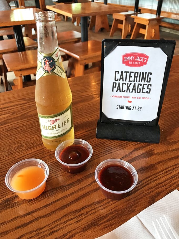 The holy trinity of barbecue sauces—each offering a different path to flavor enlightenment—alongside a cold beer for proper decision-making.