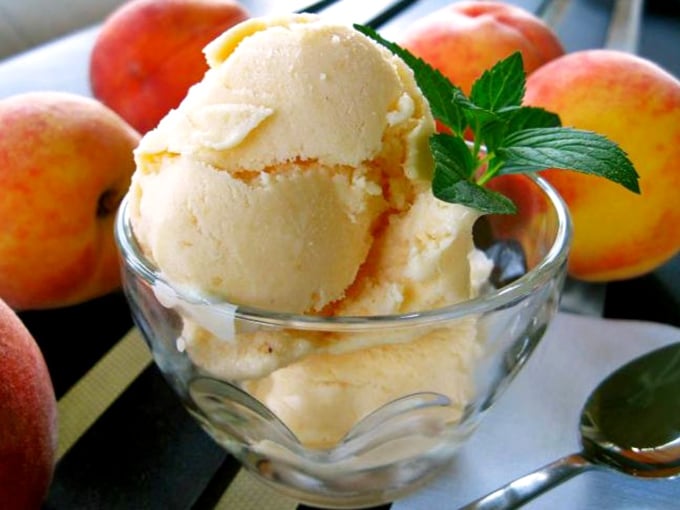 Homemade peach ice cream scooped into a simple glass bowl – summer captured in dairy form, no complications required.