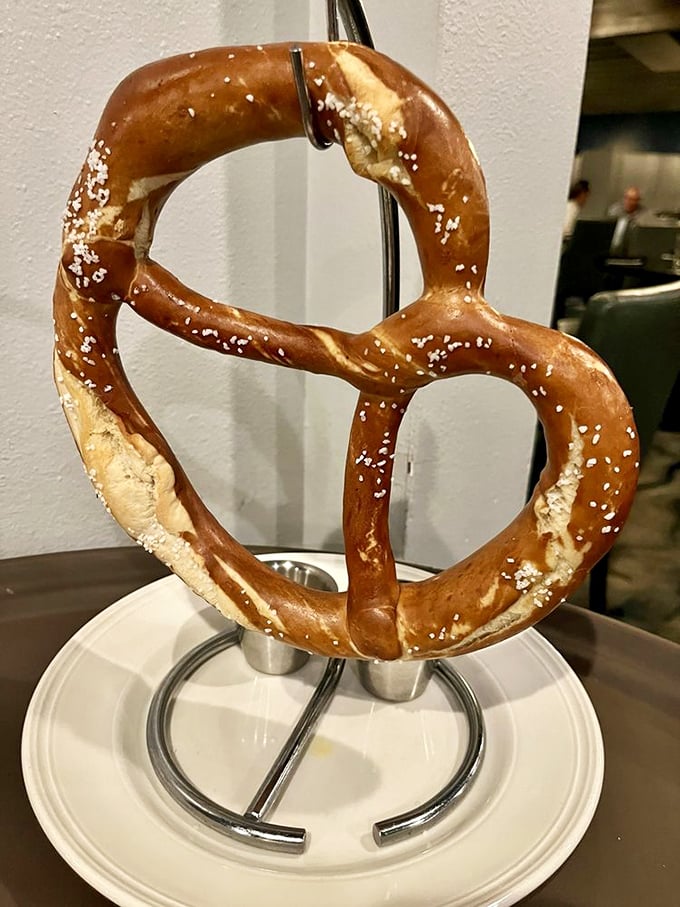 This pretzel isn't just a snack—it's architectural genius hanging from its own display stand, demanding to be photographed before devoured.