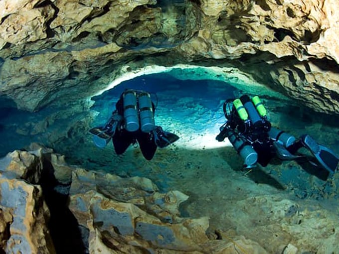 The underwater explorers' ultimate playground – cave divers illuminate limestone passages shaped by millennia of flowing water.