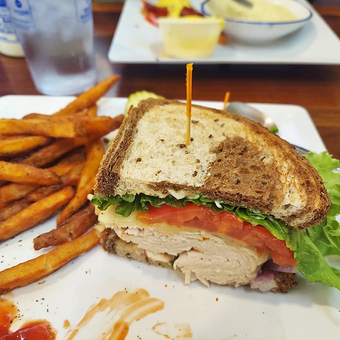 This turkey sandwich isn't just lunch—it's architecture. Layers of fresh ingredients stacked between toasty bread with sweet potato fries standing guard.