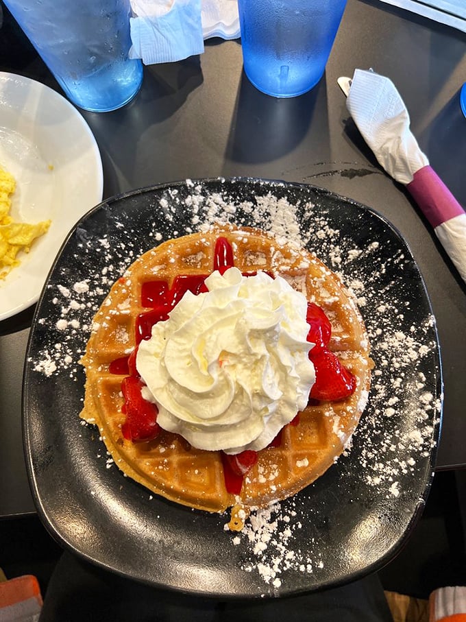 A waffle adorned with strawberries and whipped cream—proof that sometimes the simplest pleasures are the most profound. Breakfast as art.