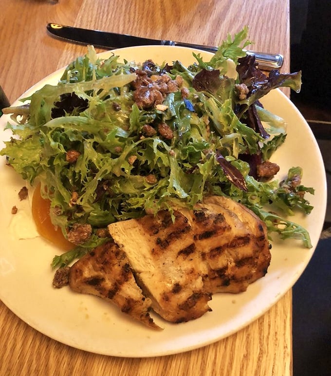 A salad that actually excites—grilled chicken alongside vibrant greens and what appears to be candied nuts, proving healthy can be heavenly.