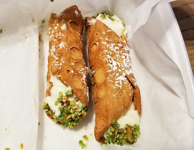 These cannoli aren't just dessert—they're edible treasure chests with crisp shells guarding creamy ricotta filling, dusted with powdered sugar and pistachios.