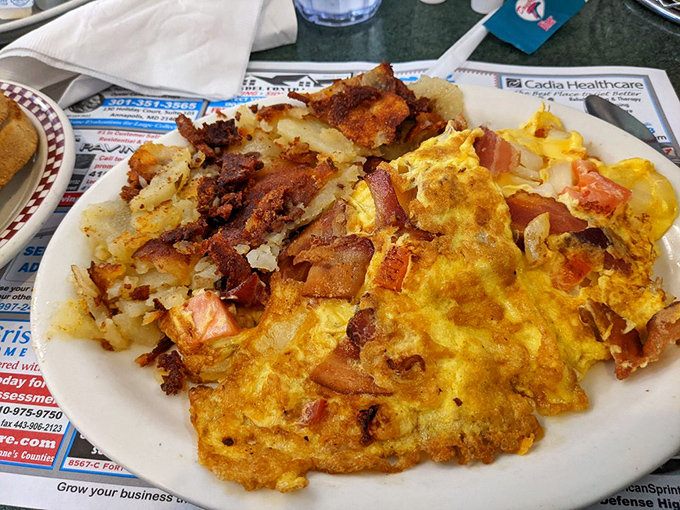 This omelet doesn't just contain bacon—it embraces it, celebrates it, throws it a parade alongside perfectly crisped home fries.