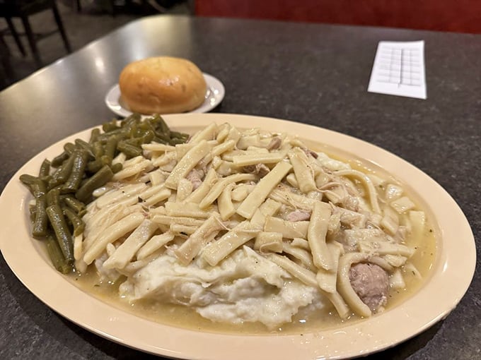 Chicken and noodles swimming in gravy with a side of green beans—the kind of plate that makes you want to call in sick tomorrow.