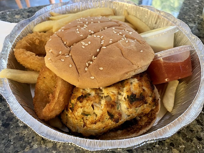 The crab cake sandwich arrives like edible architecture – golden-crusted Maryland blue crab elevated to sandwich royalty with a side of crispy rings.