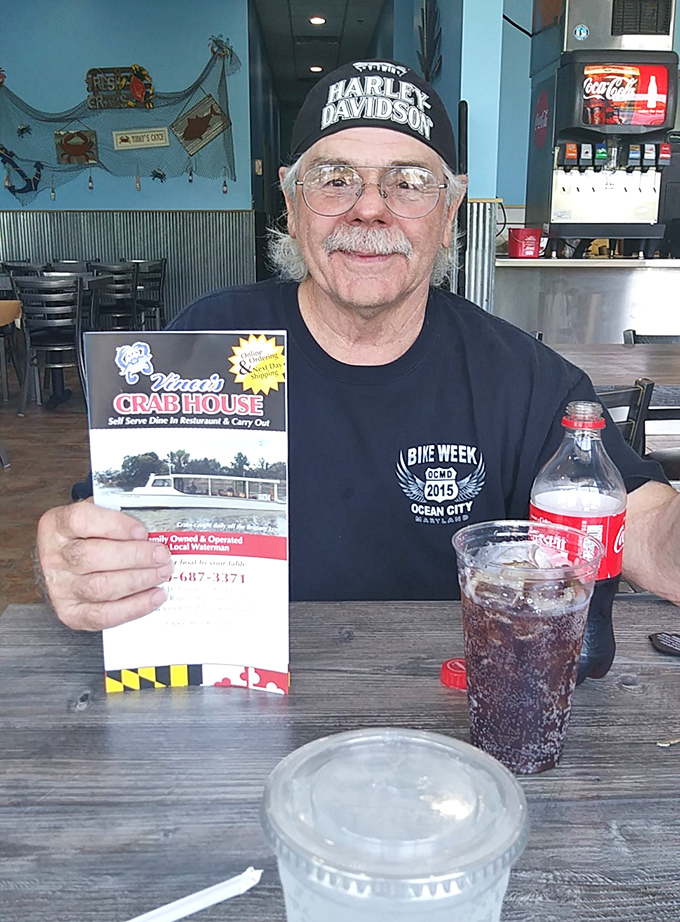 A satisfied customer shows off the menu—proof that in the religion of Maryland seafood, everyone's welcome to worship at this altar.