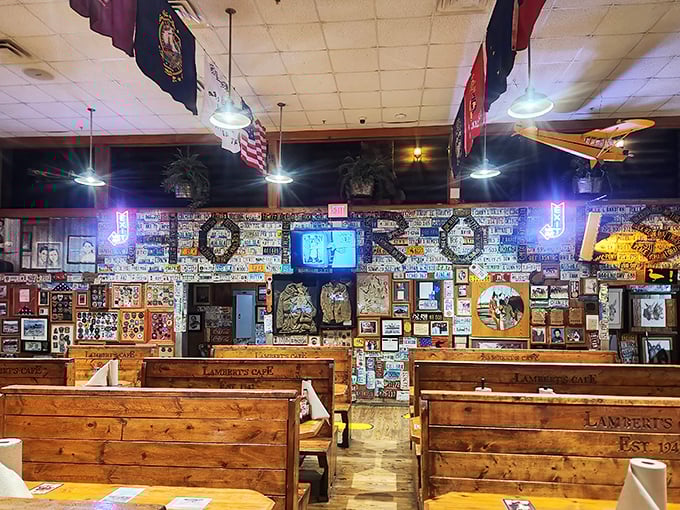 The dining room at Lambert's isn't just decorated—it's curated chaos, where every inch tells a story and every flag represents a visitor's home state.