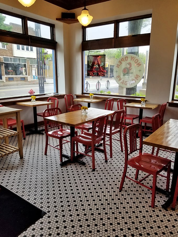 The dining area's red chairs aren't just seating—they're front-row tickets to the theater of Wauwatosa life unfolding outside those big windows.