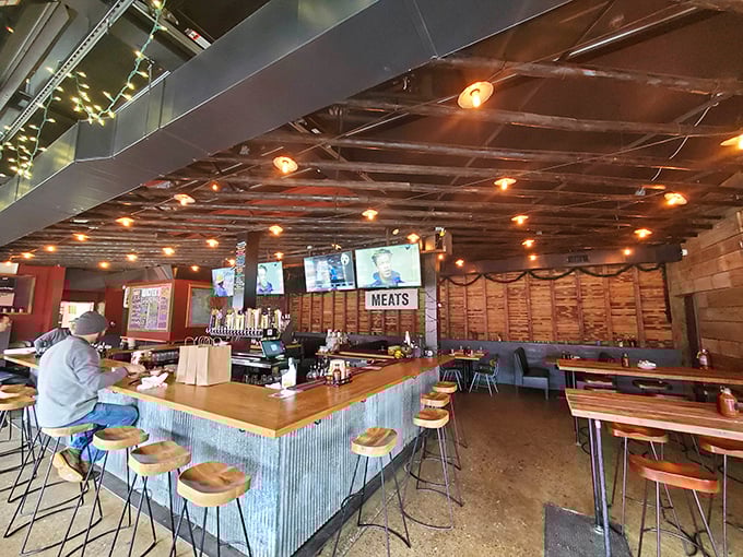 The dining area blends industrial chic with barbecue joint authenticity – exposed ceiling, wooden tables, and a sign that simply states "MEATS."