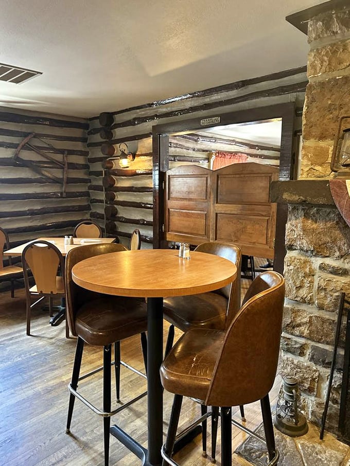 Stone fireplace meets log cabin walls – the kind of cozy corner where conversations flow as easily as the drinks.