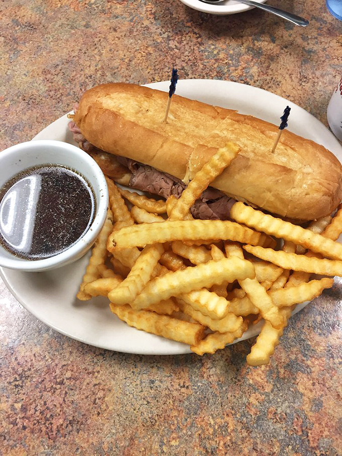 The French dip sandwich—where tender roast beef meets its soulmate in a pool of savory au jus, with crispy fries standing by for moral support.