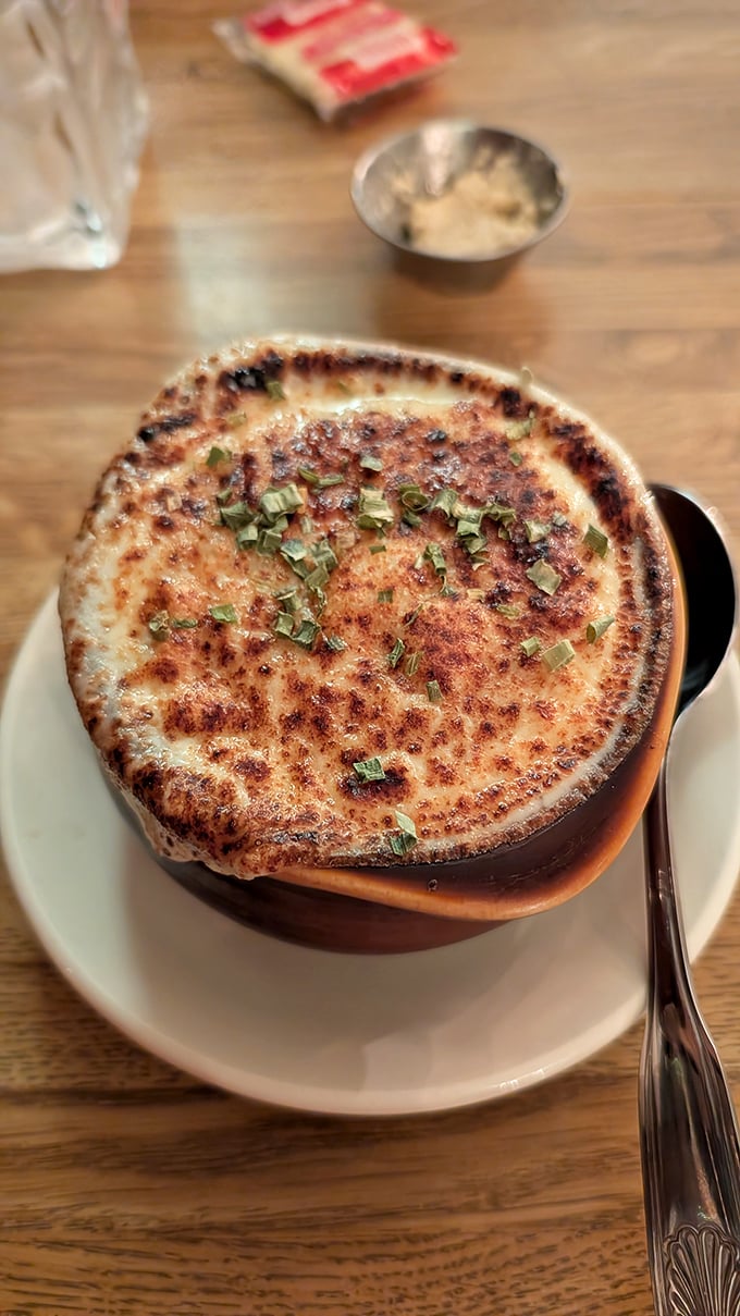 French onion soup wearing its traditional cheese cap like a crown—a bubbling cauldron of comfort that demands to be broken into.