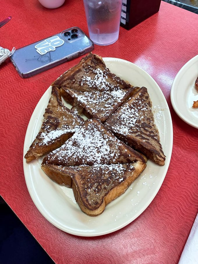 French toast cut into triangles because somehow it tastes better that way. The powdered sugar snowfall makes it Instagram-worthy before that was a thing.