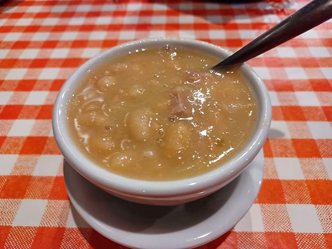 A steaming bowl of ham and bean soup on a checkered tablecloth – the kind of simple perfection that warms you from the inside out.