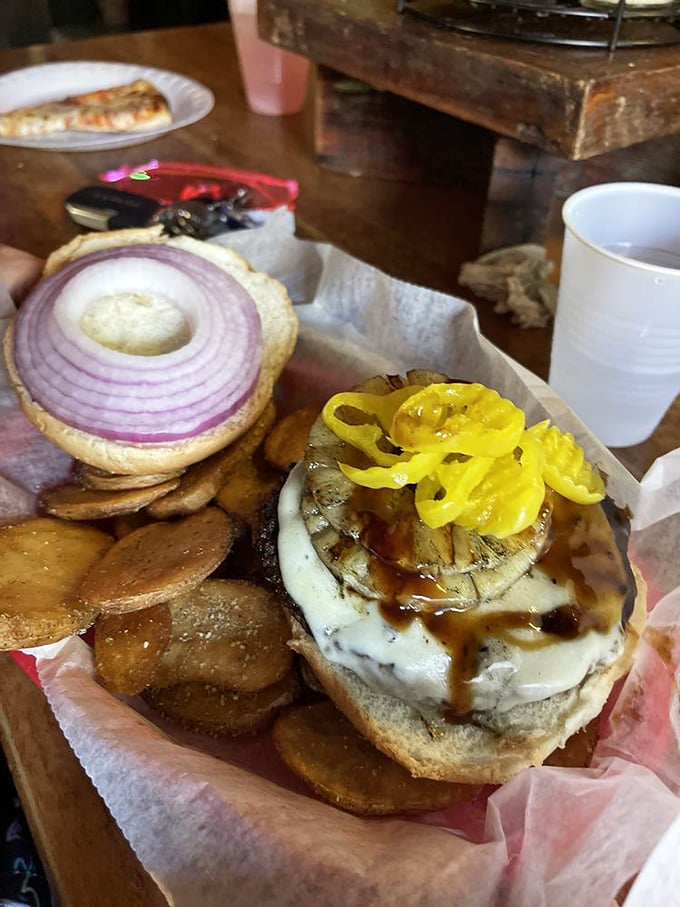 This burger isn't just topped—it's architecturally enhanced with a tower of grilled onions, peppers, and mushrooms that defy gravity.